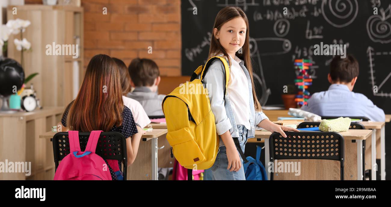 Little girl with backpack in classroom Stock Photo - Alamy