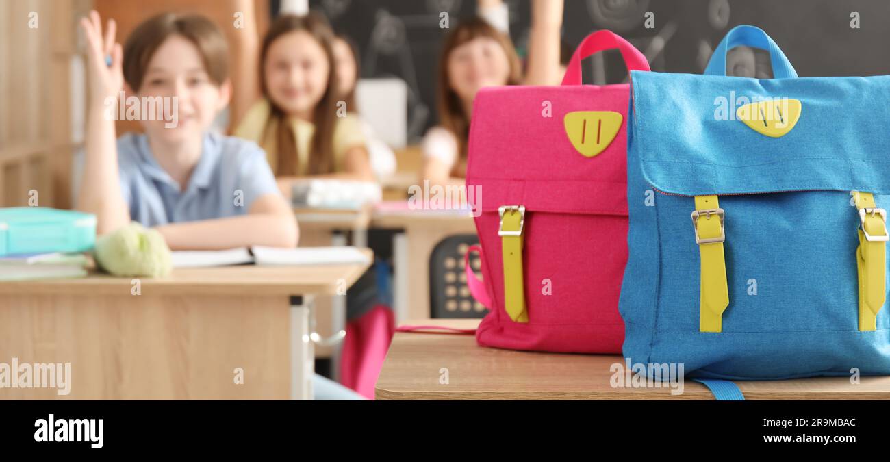 Children's backpacks on desk in classroom Stock Photo - Alamy