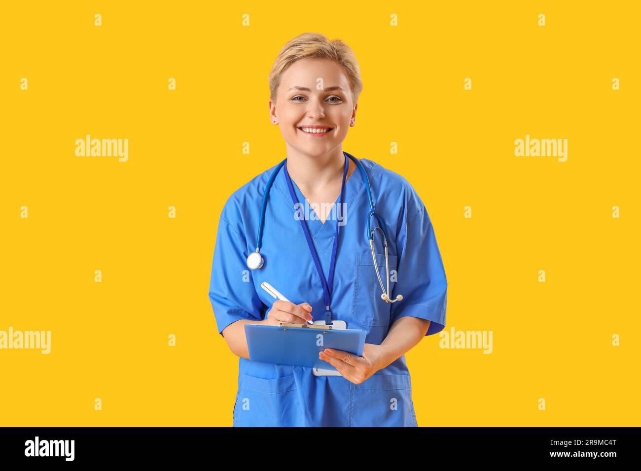 Female medical intern with clipboard on yellow background Stock Photo ...