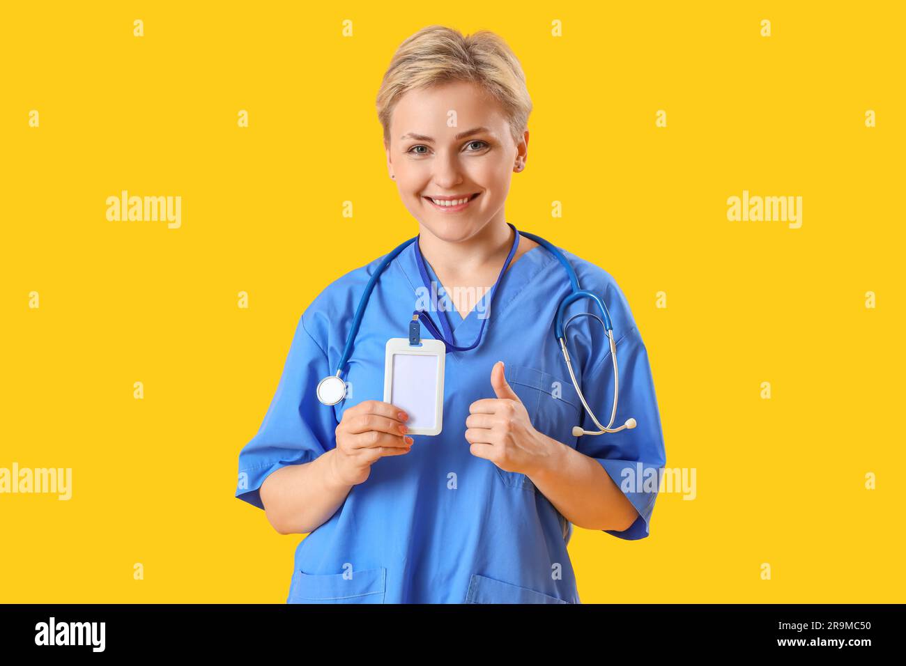 Female medical intern with badge showing thumb-up on yellow background ...