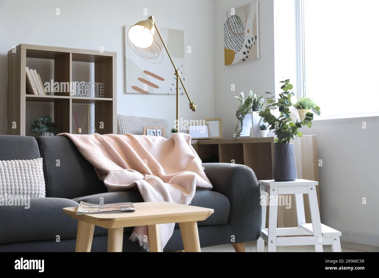 Interior of light living room with glowing lamp, table and sofa Stock ...