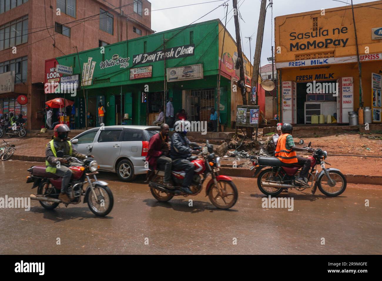 Three motorcycle taxis, known as boda bodas, navigate a road in Kampala ...