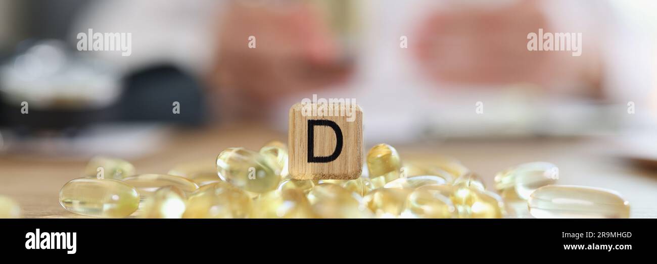 Transparent yellow capsules and wooden cube with letter d Stock Photo ...