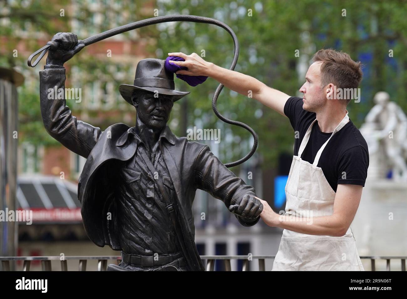 A life-sized bronze statue of the character Indiana Jones being cleaned ...