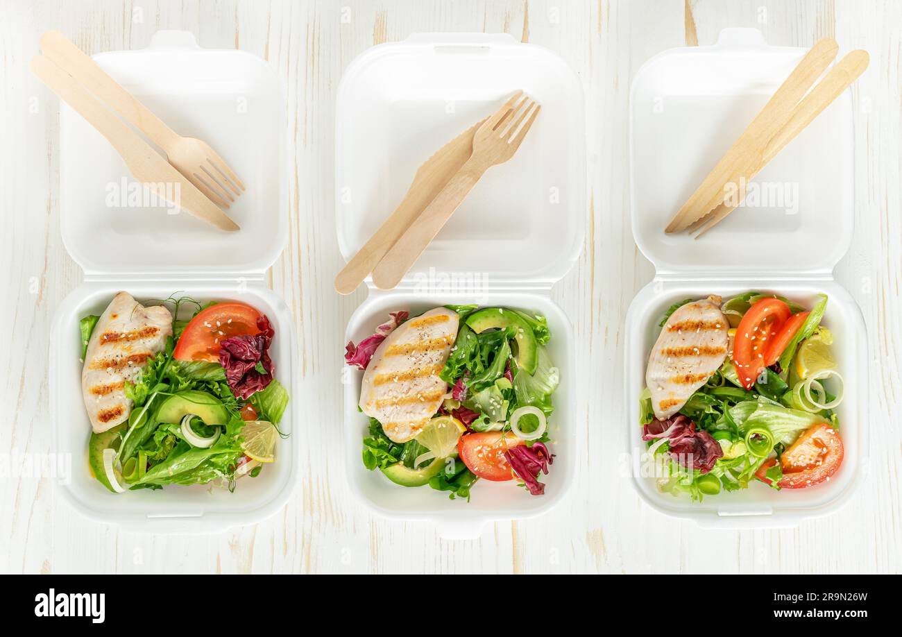 Healthy food delivery. Lunch boxes with fresh salad and grilled chicken ...