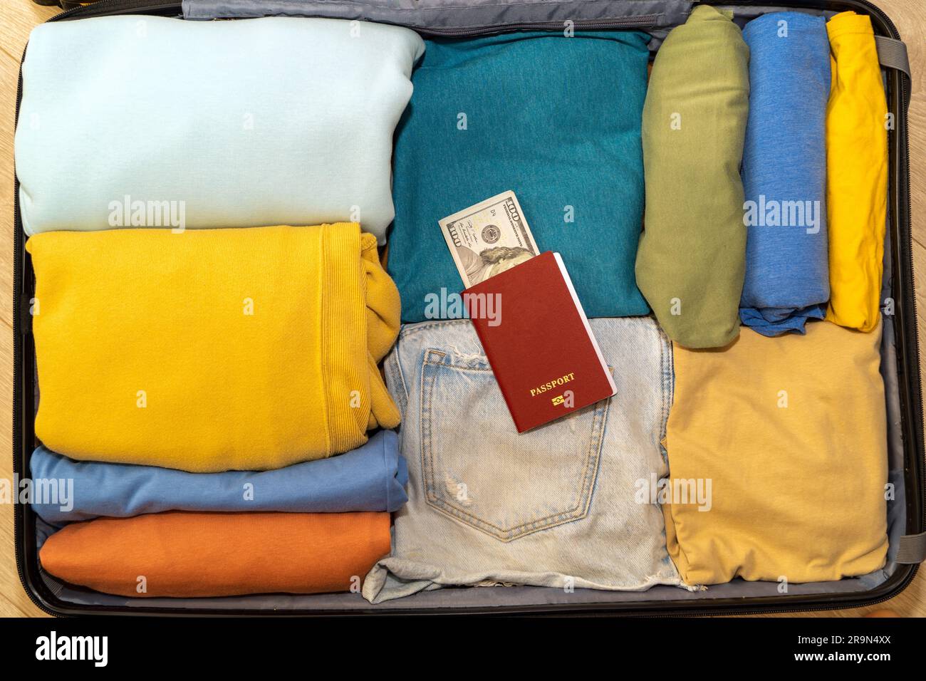 Top down view of a suitcase with neatly stowed women's clothing, a ...