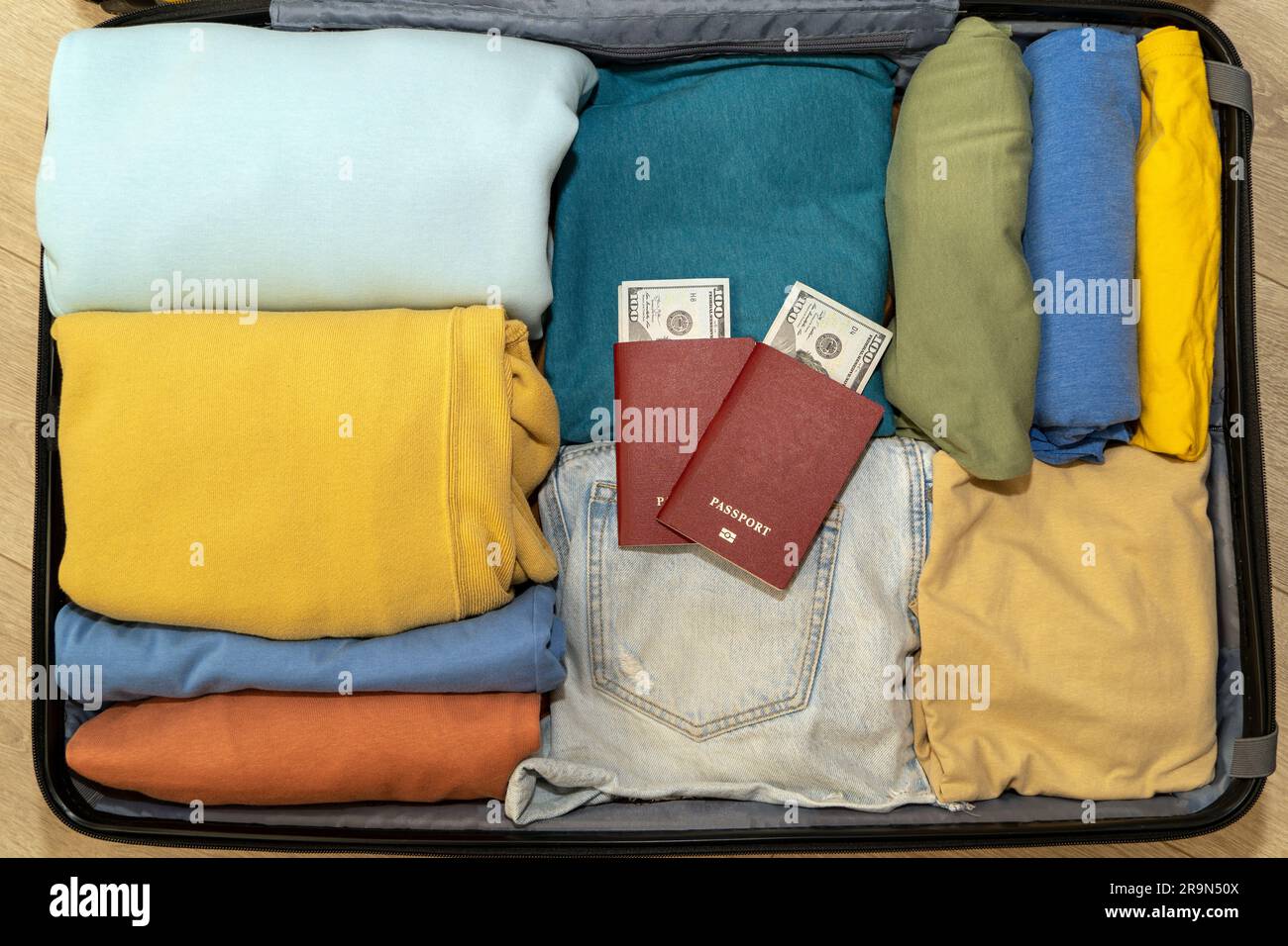 Top view of a suitcase with neatly stowed women's clothing, a passport ...