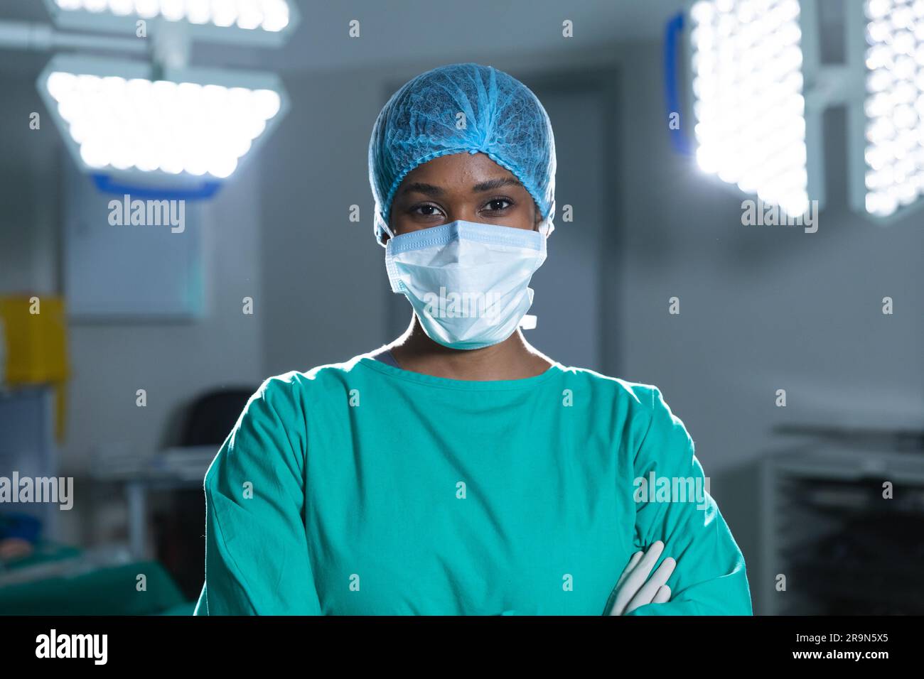 Portrait of african american female surgeon wearing surgical gown and face mask in operating ...
