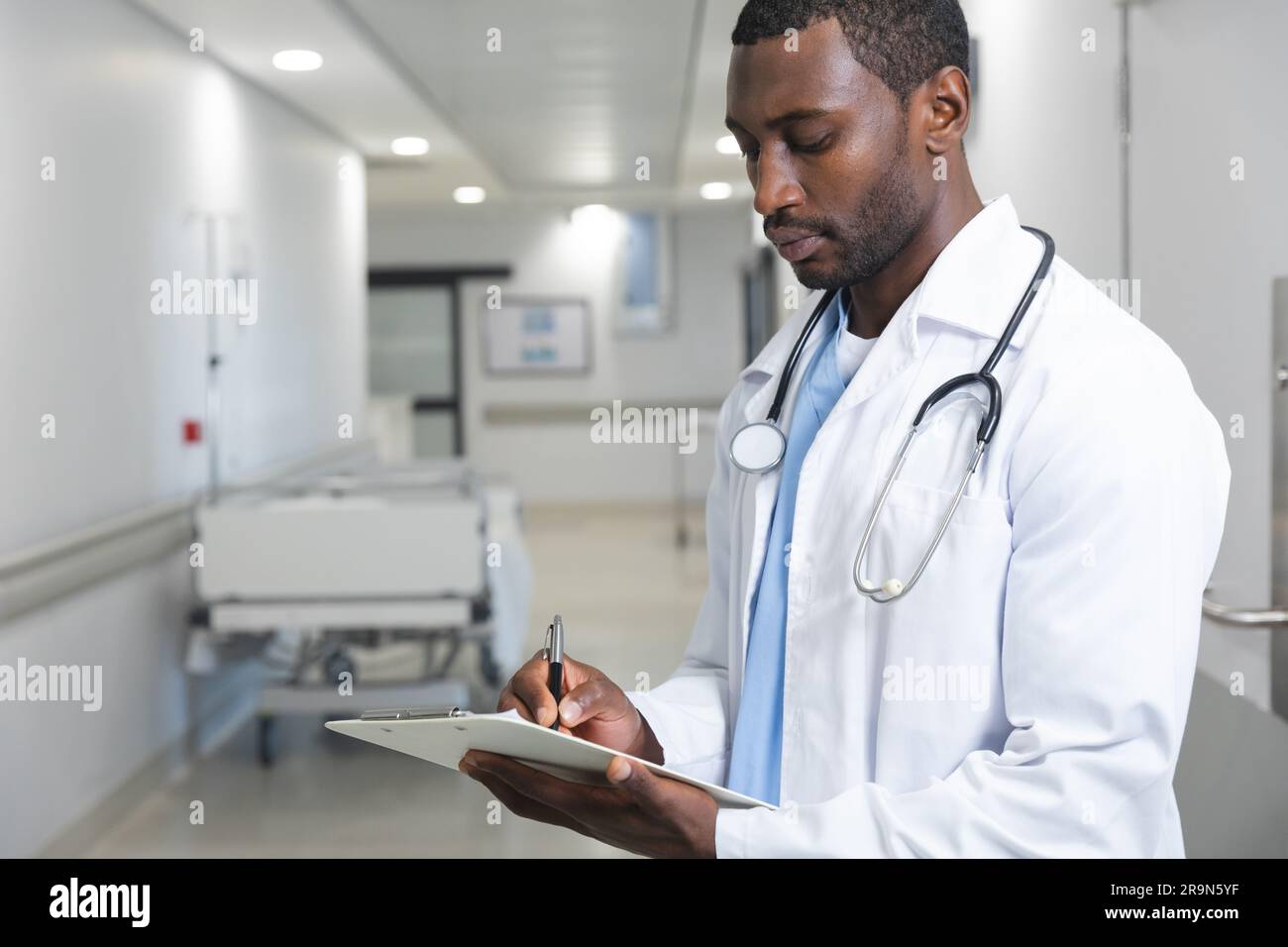 African american male doctor wearing lab coat and stethoscope, holding ...