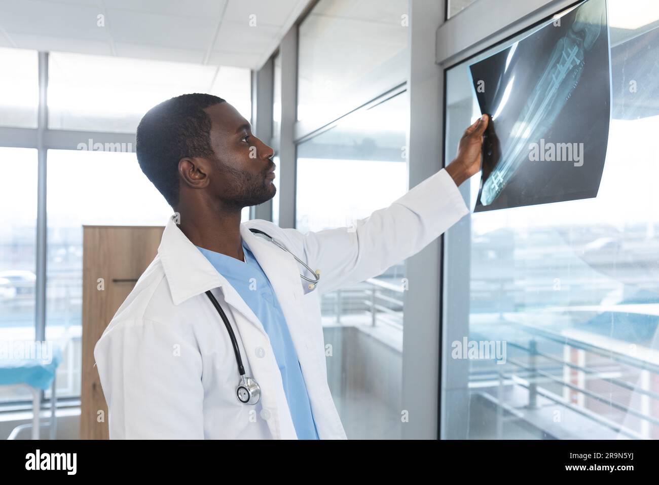 African american male doctor wearing lab coat and stethoscope, holding ...