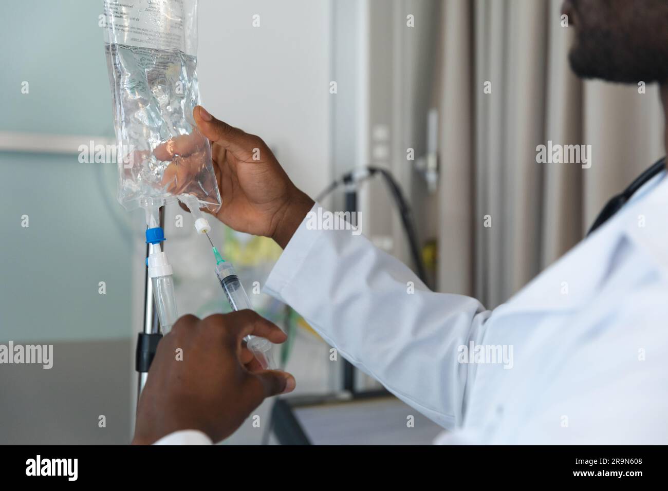 African american male doctor wearing lab coat, applying drip in ...
