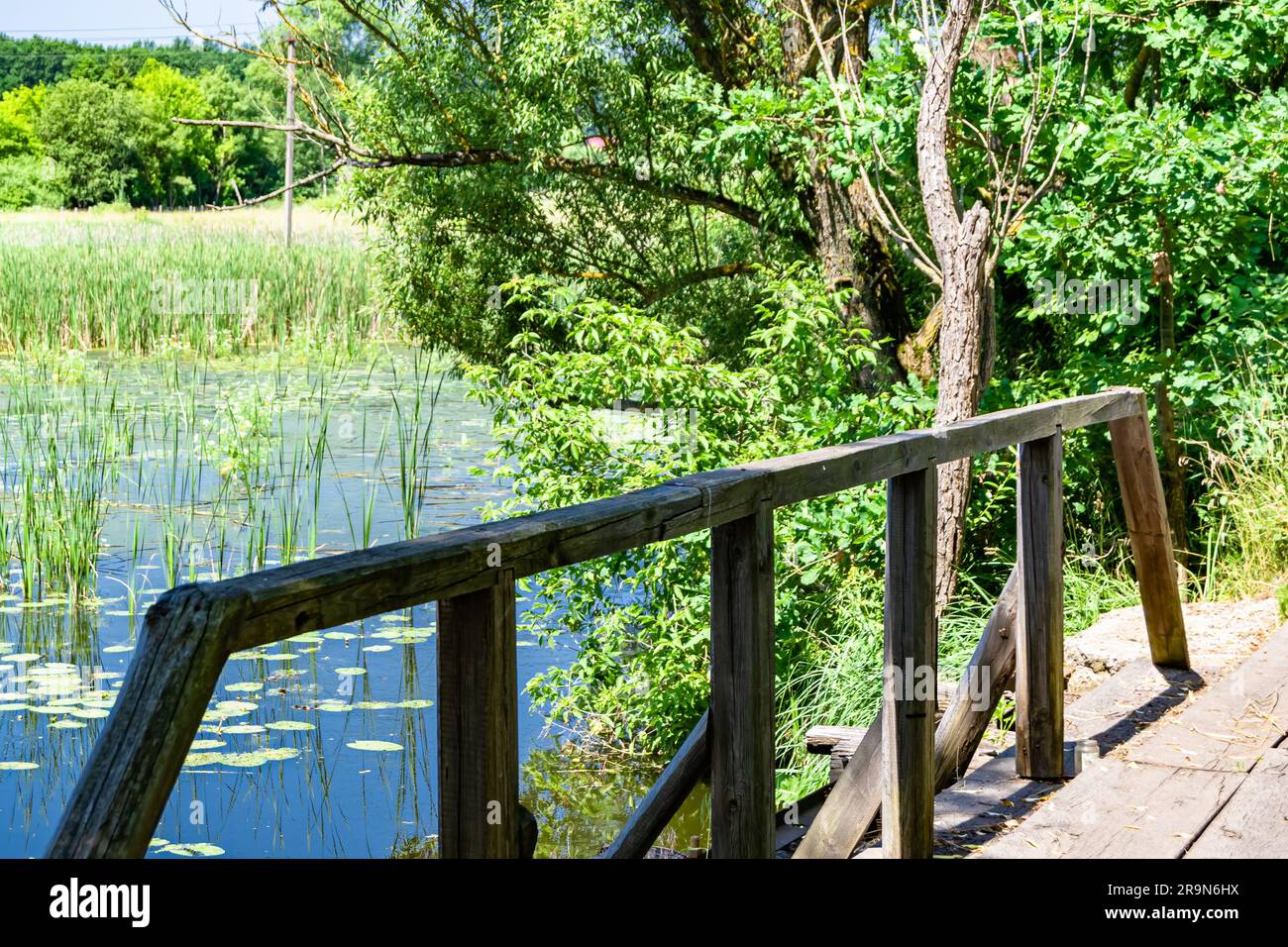 Beautifully standing old wooden bridge over river in colored background ...