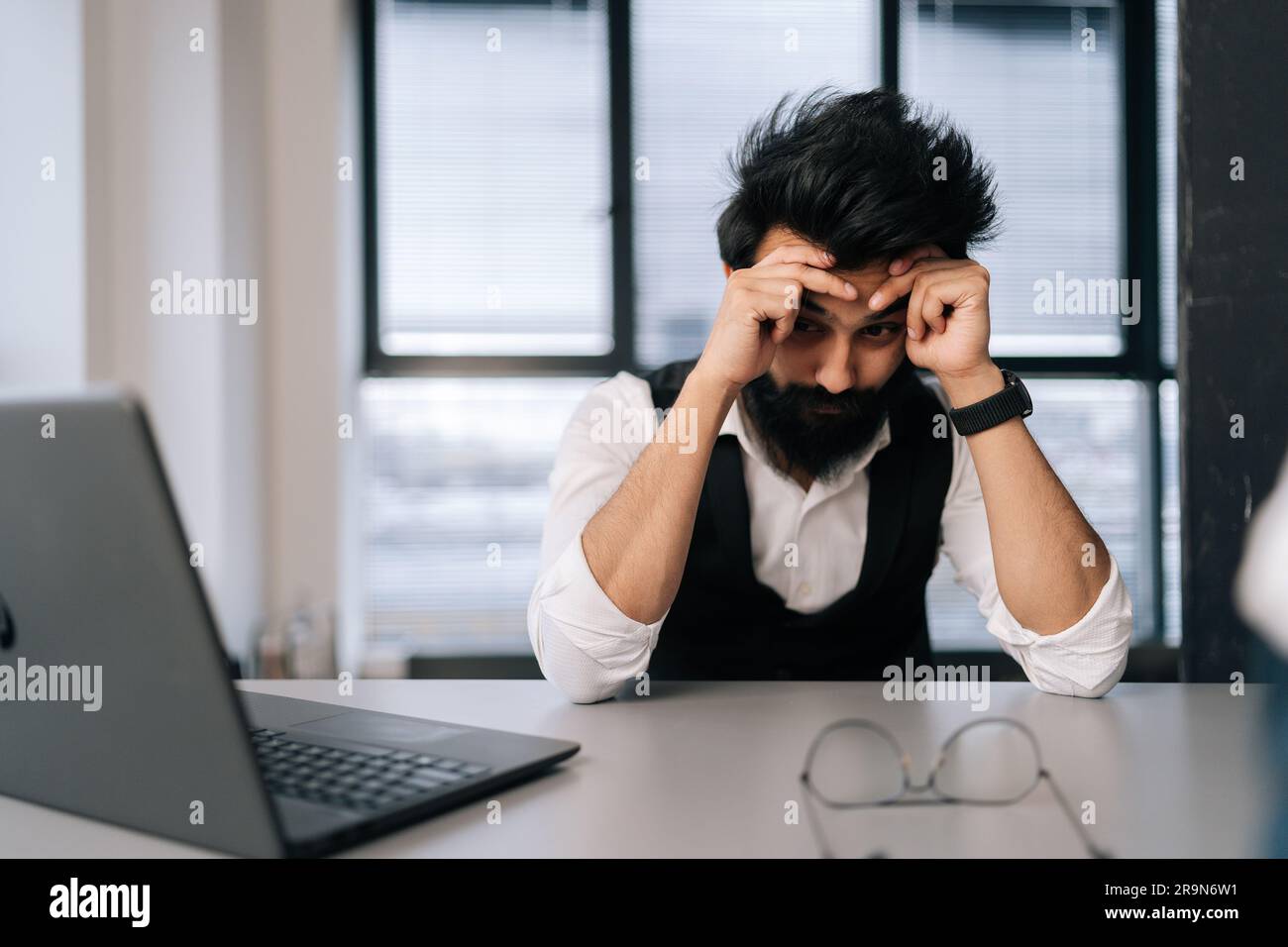 Portrait of tired Indian business woman in stress works at laptop while ...