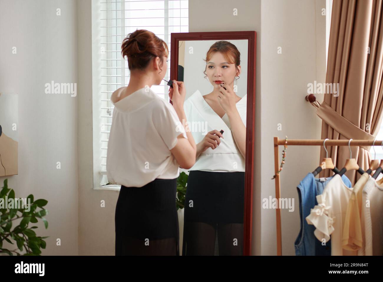 Transgender woman applying red lipstick on front of mirror wine getting ...