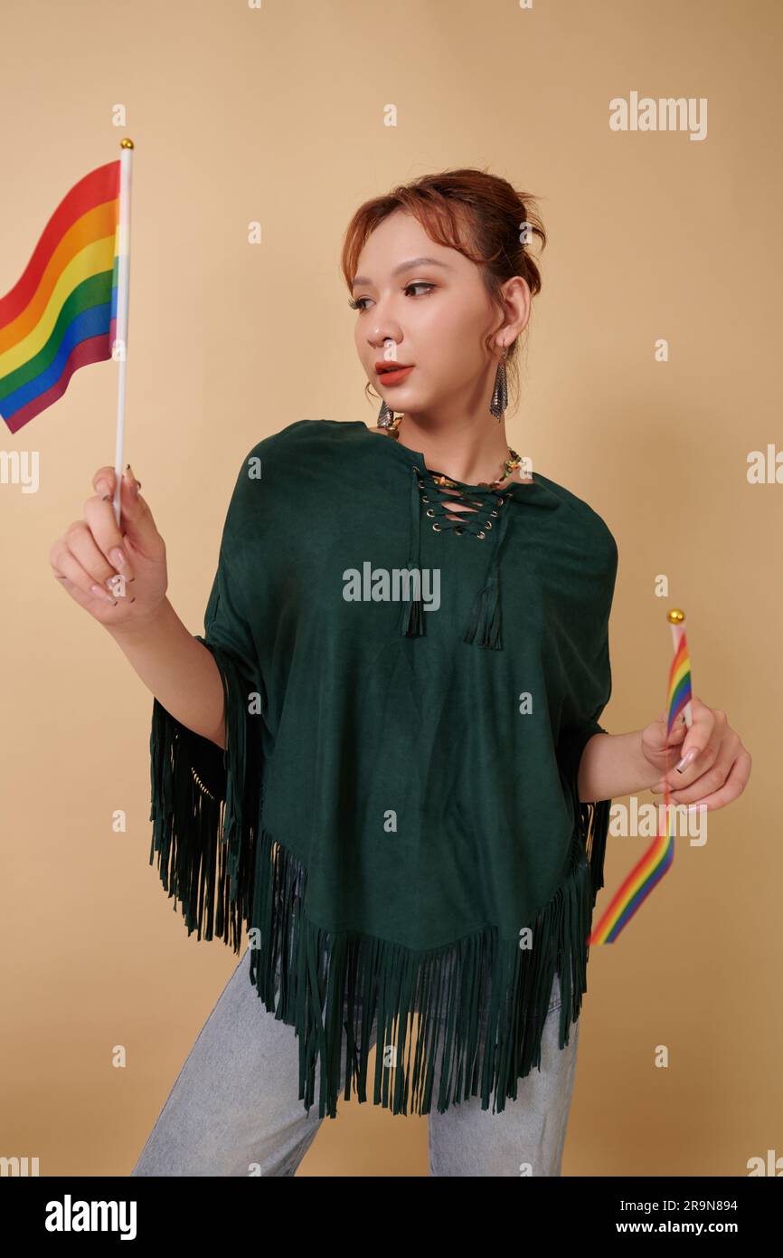 Young transgender woman posing with two rainbow flags, pride month ...