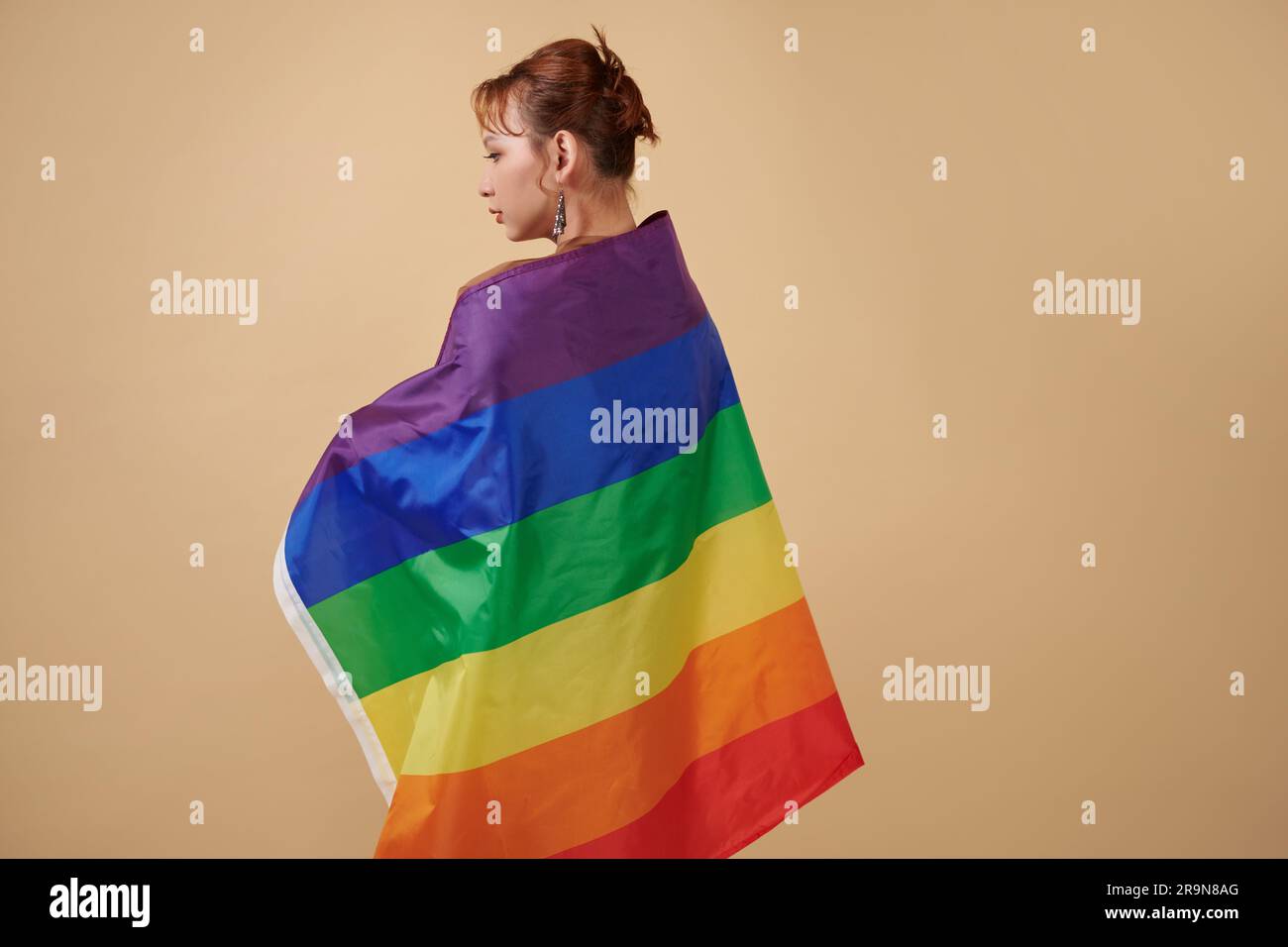Serious transgender woman wrapped in rainbow flag standing against ...