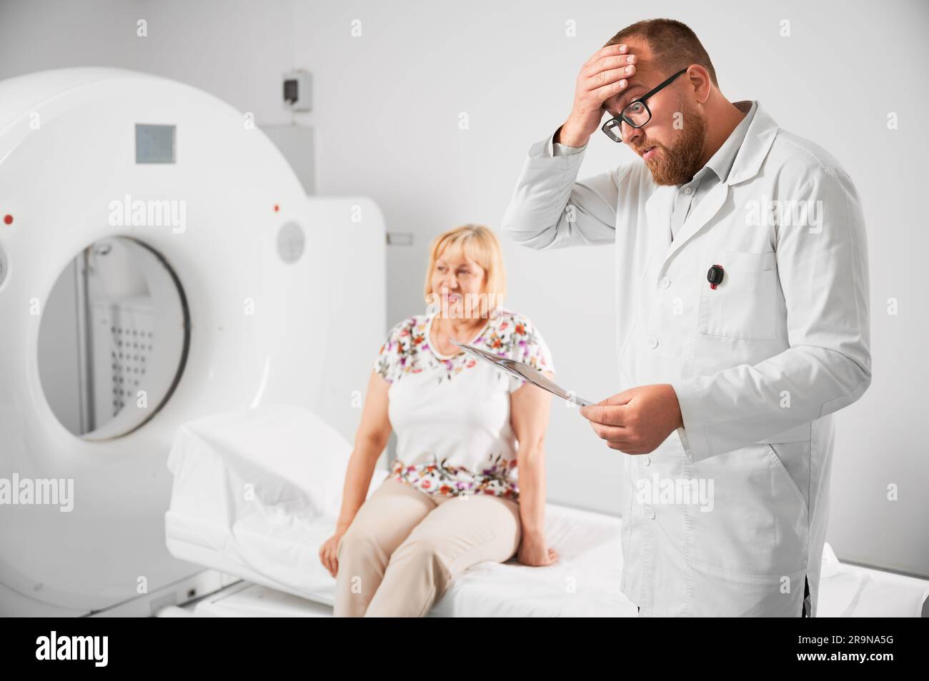 Medical computed tomography or MRI scanner. Shocked, surprised doctor looking at scan, examining ...
