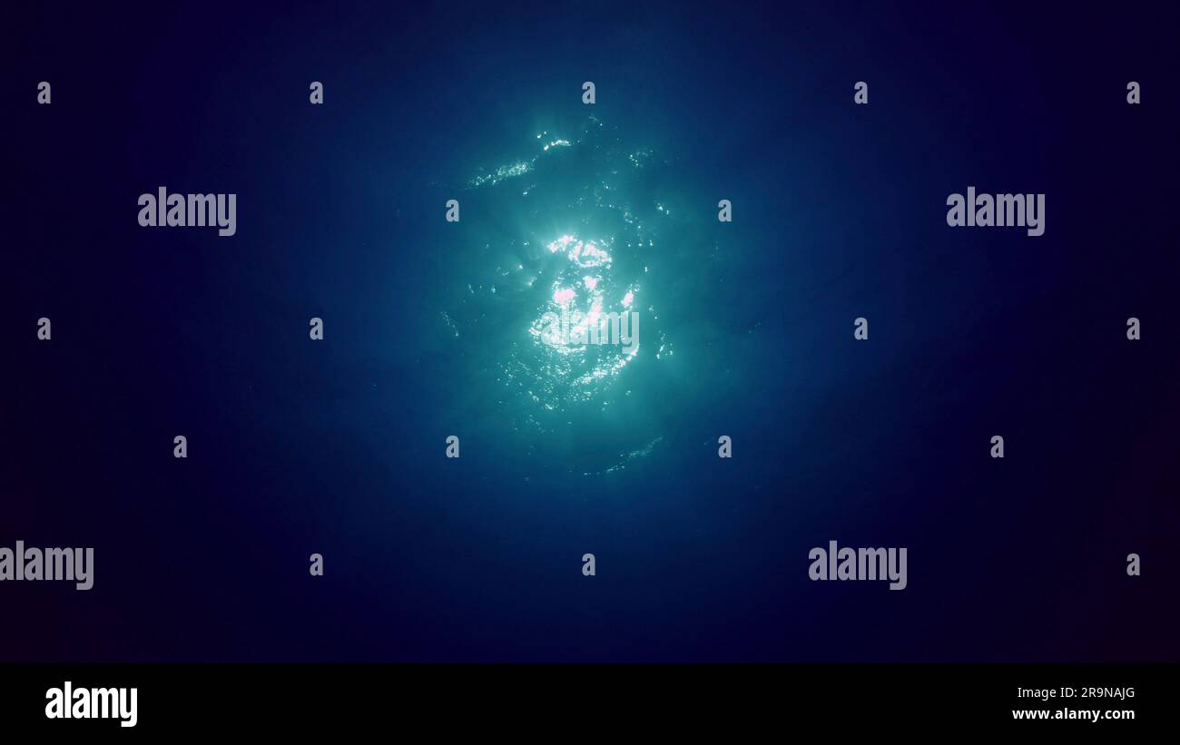 View of sun light from blue abyss, slow motion. Light filters down ...
