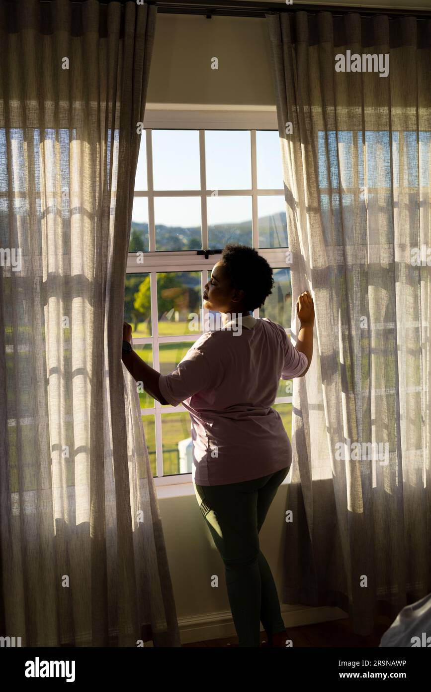 Plus size african american woman looking out window at home Stock Photo ...