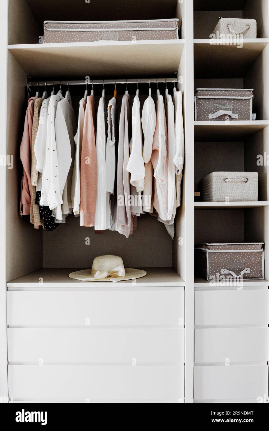 A well-organized white wardrobe with a variety of clothing items neatly ...