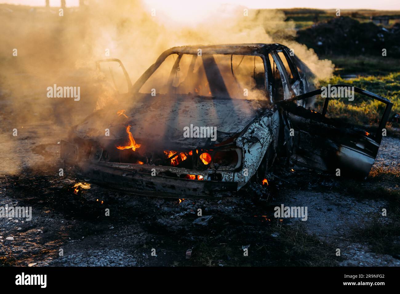 A burning old car in the forest at sunset Stock Photo - Alamy