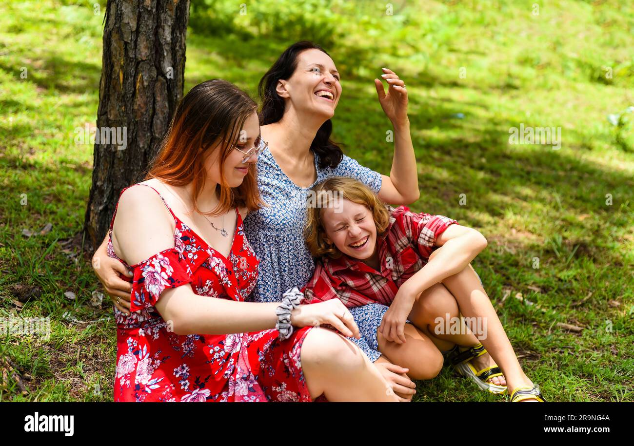 Mother hugging her teenage daughter and little daughter and laughin together with them in the ...