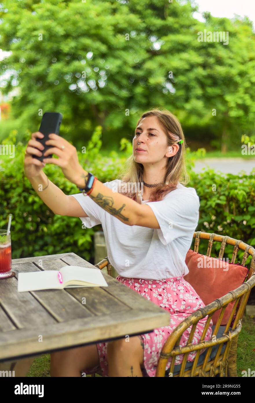 Cute woman taking a photo selfie and drinking tea in summer garden ...