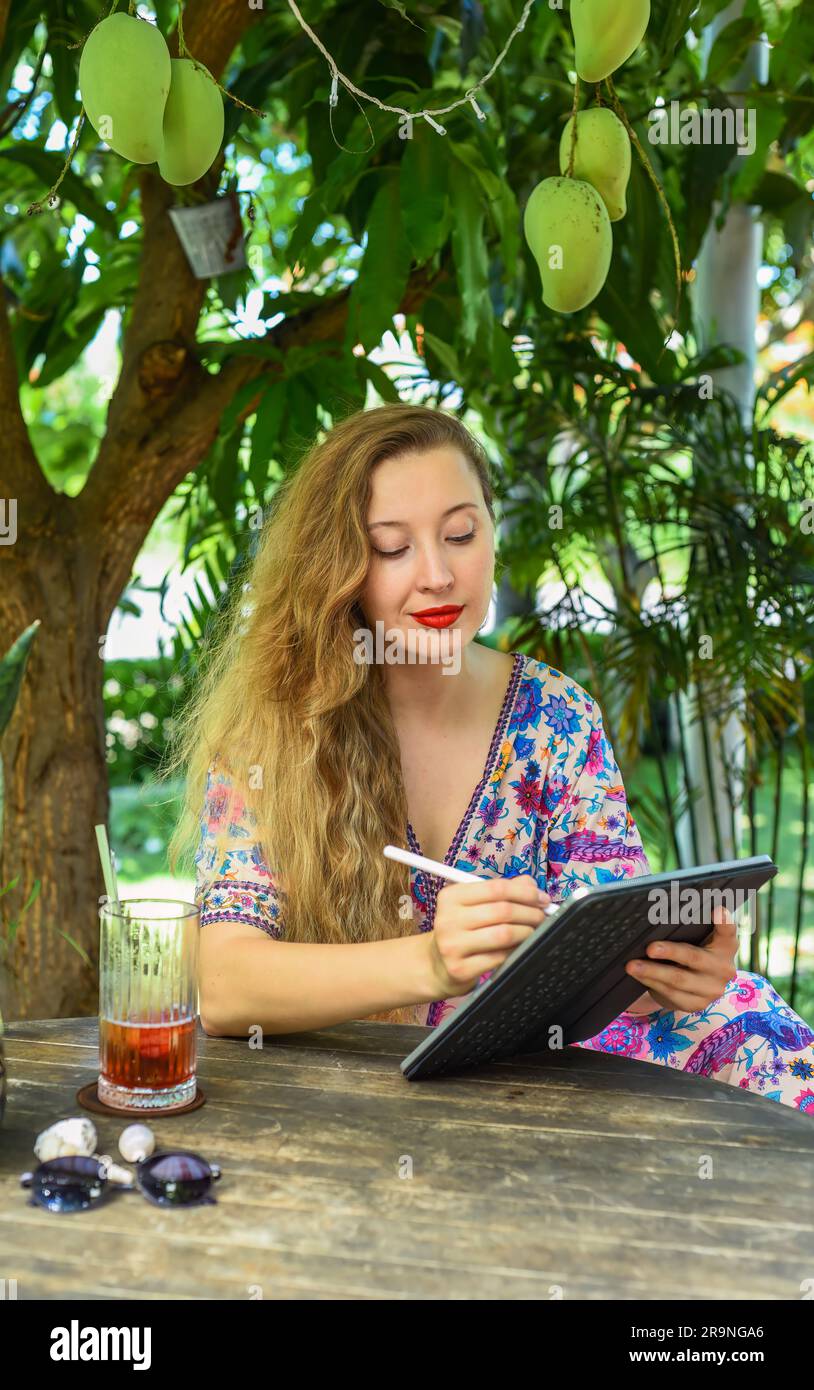 Beautiful blonde woman artist and illustrator drawing, sitting by the ...