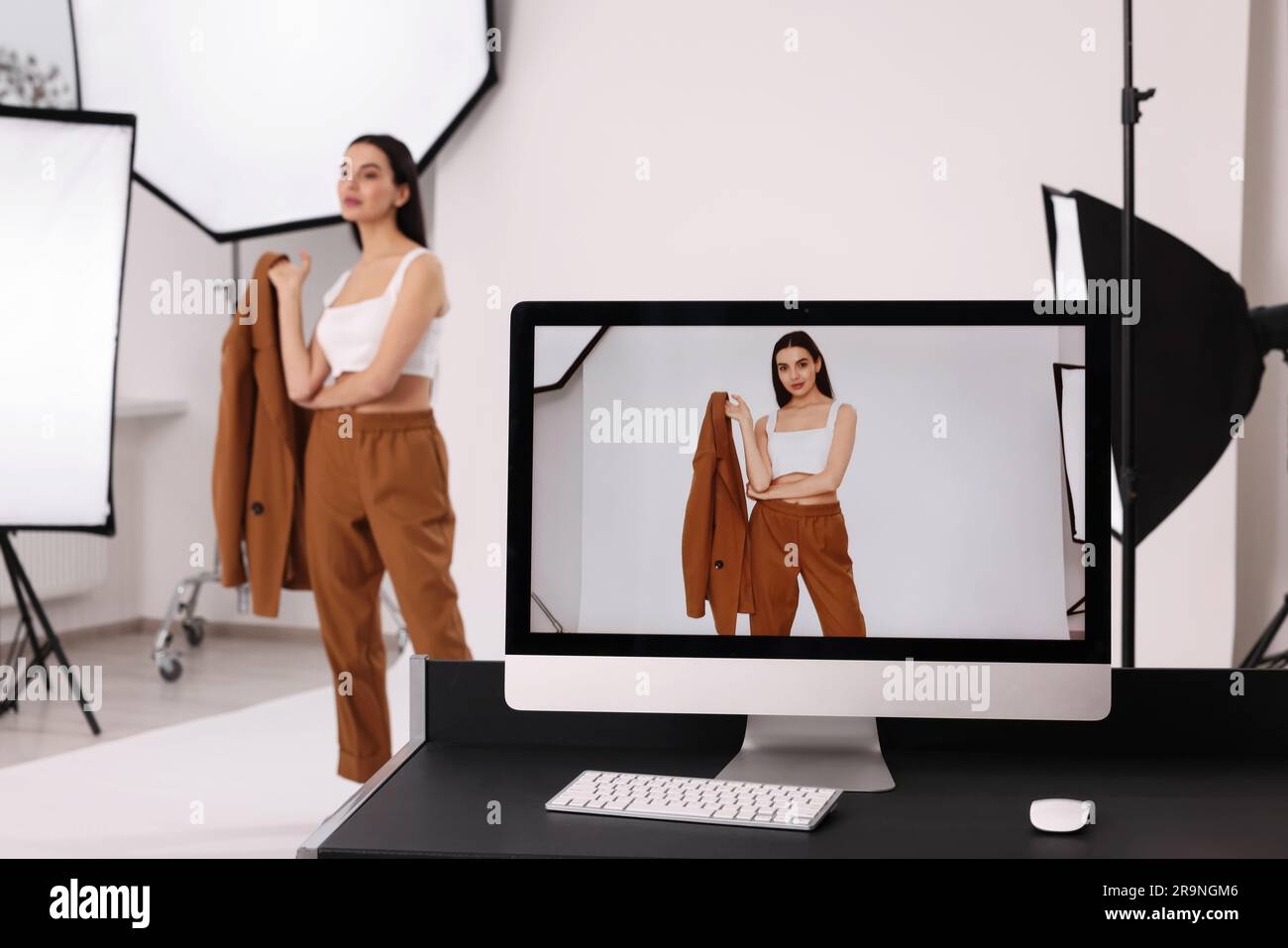 Beautiful model posing in modern photo studio, focus on computer screen ...