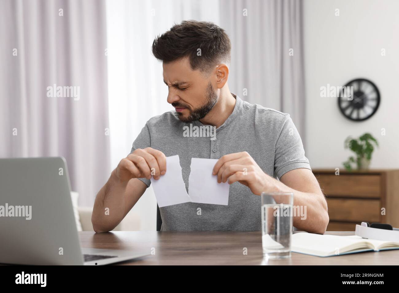 Man ripping photo at table indoors. Divorce concept Stock Photo - Alamy