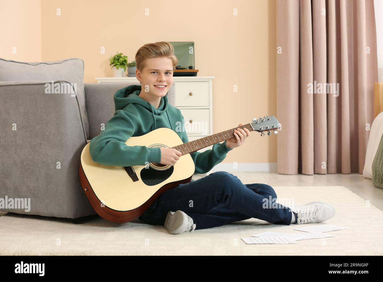 Teenage boy playing acoustic guitar in room Stock Photo - Alamy