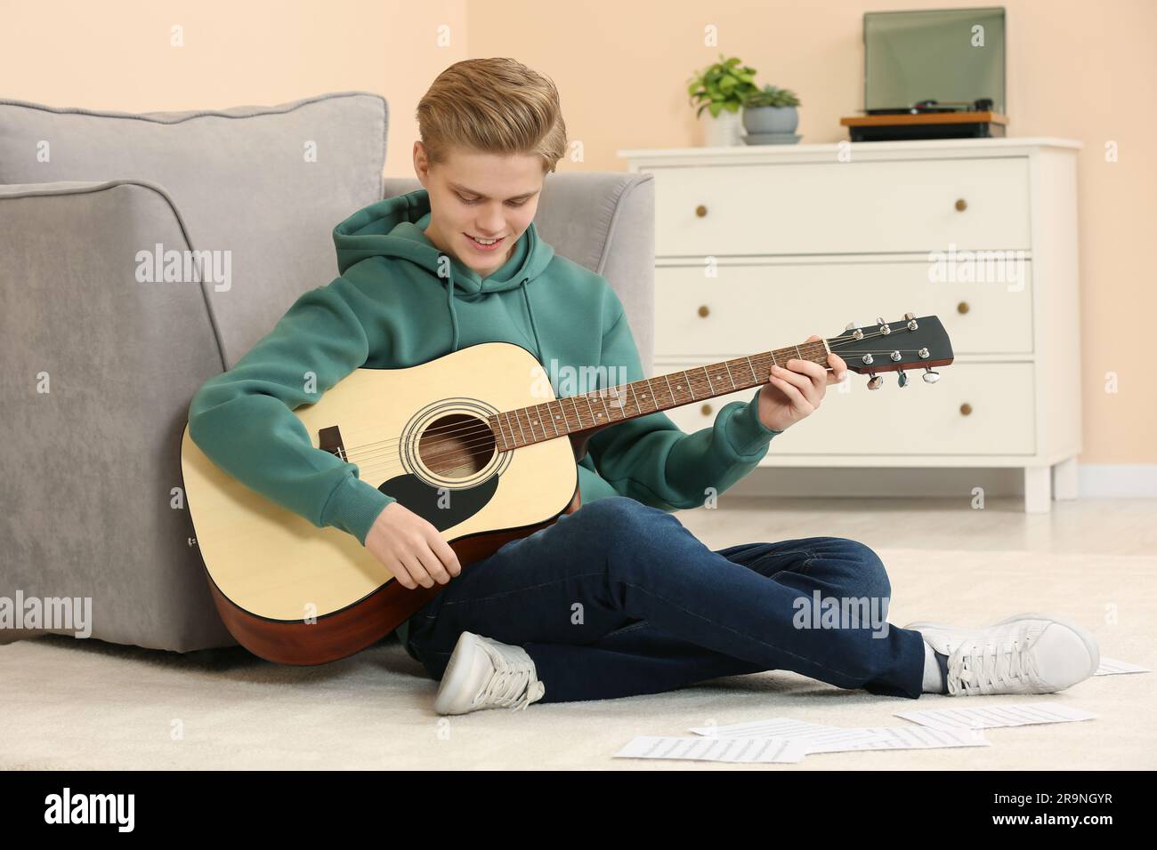 Teenage boy playing acoustic guitar in room Stock Photo - Alamy