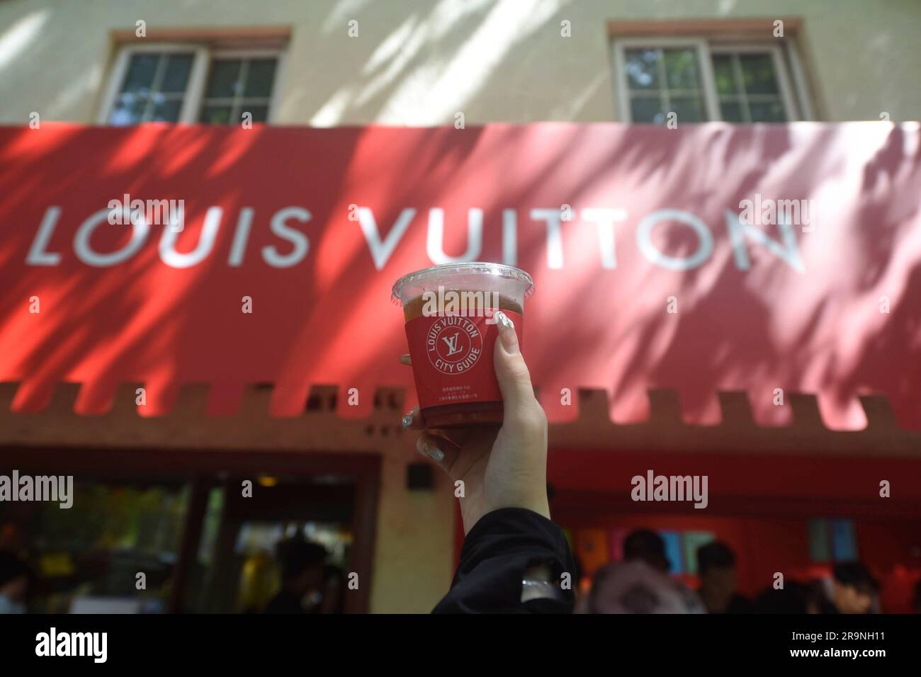 A fan holds up a cup of Louis Vuitton coffee outside a temporary Louis ...