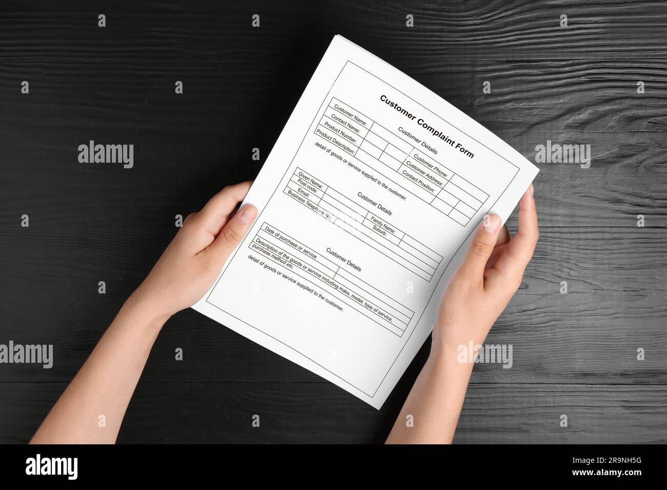 Woman holding complaint form at black wooden table, top view Stock ...
