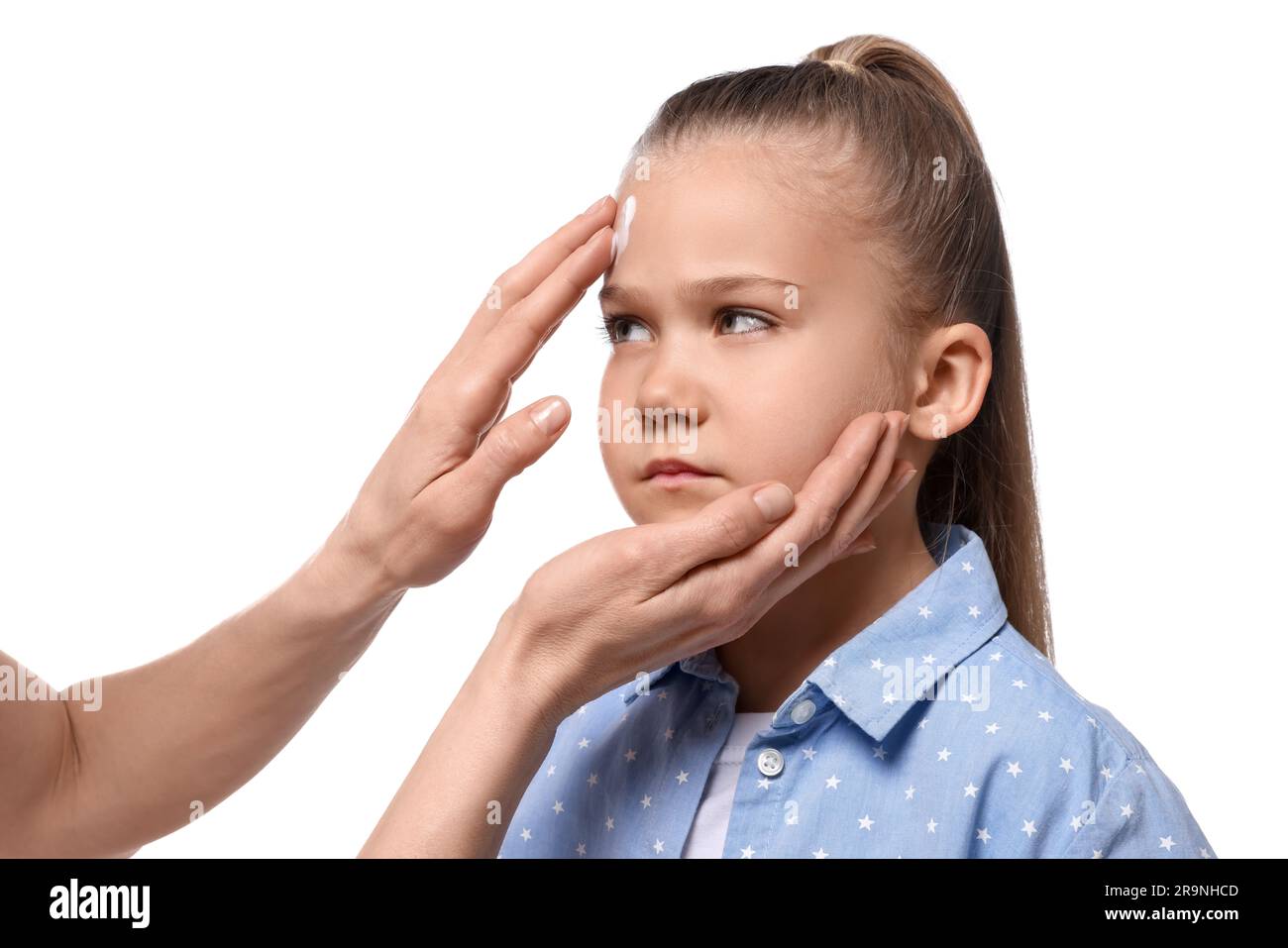 Mother applying ointment on her daughter's forehead against white ...