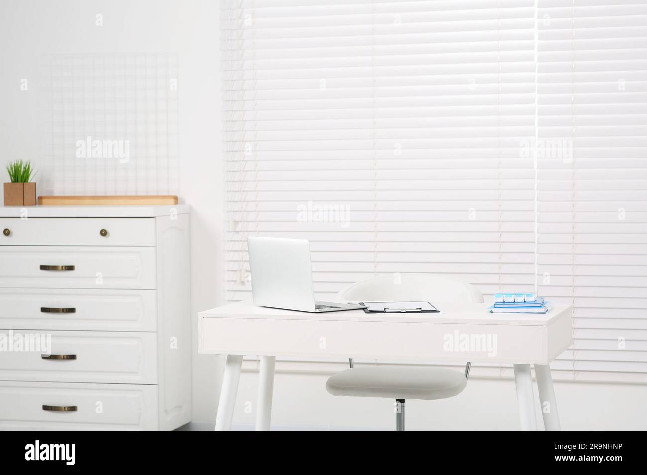 Beautiful office with laptop on white table, chair and chest of drawers ...