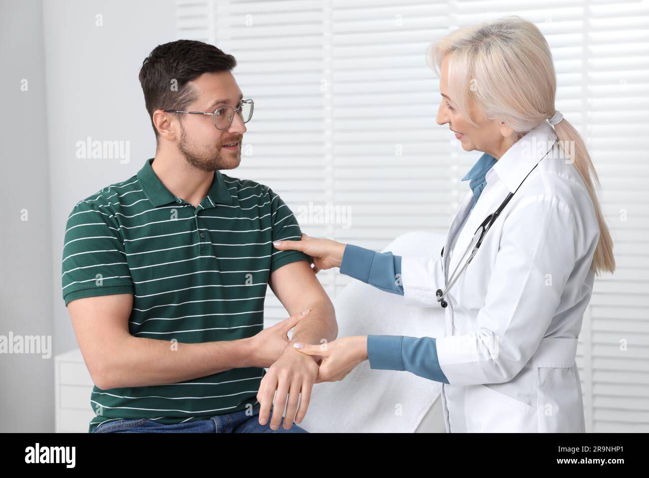 Doctor checking patient's pulse during consultation in clinic Stock ...