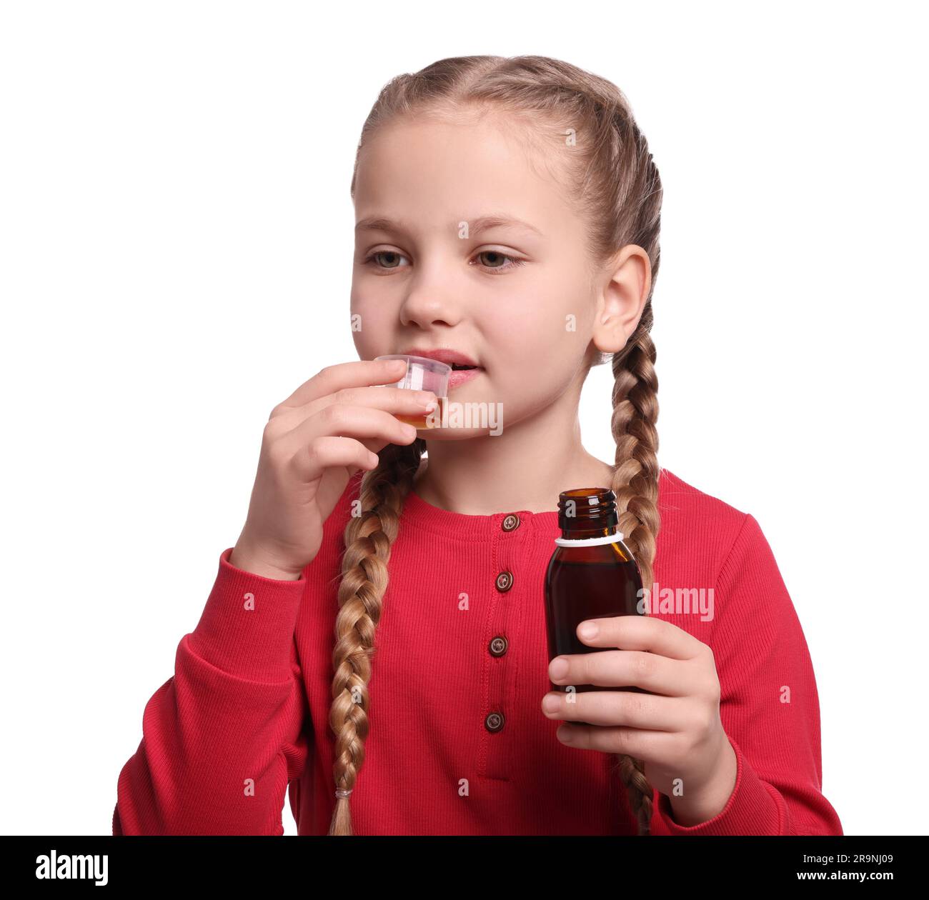 Cute girl taking syrup from measuring cup on white background Stock ...