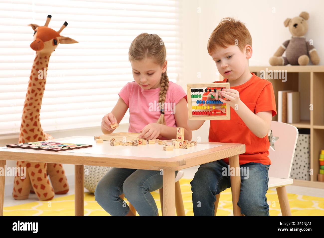 Children playing with different math game kits at desk in room. Study ...