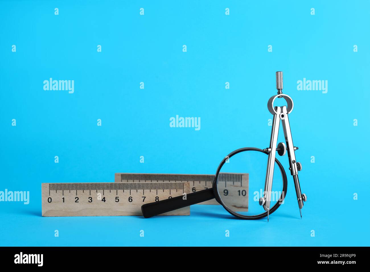Rulers, magnifying glass and compass on light blue background Stock ...