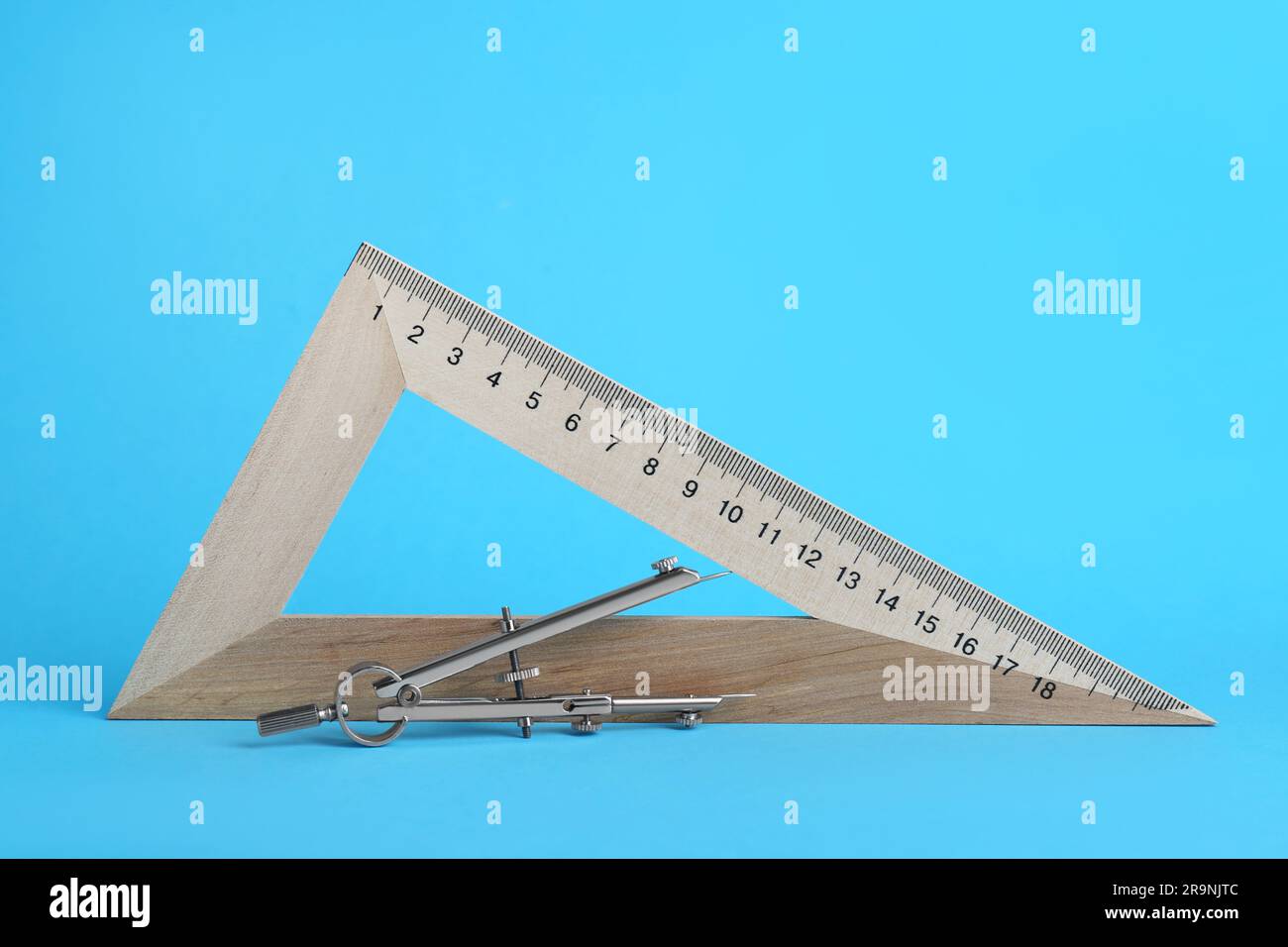 Triangle ruler and compass on light blue background Stock Photo - Alamy