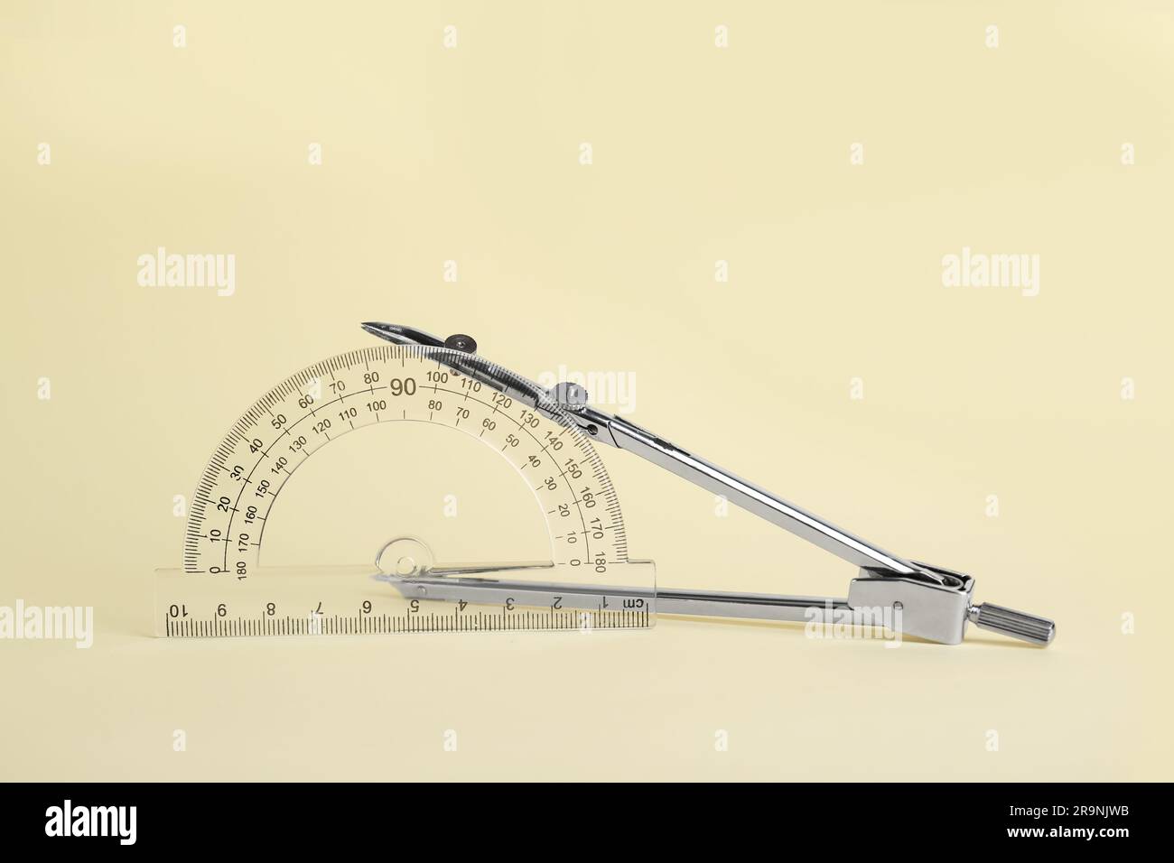 Protractor and metal compass on yellow background Stock Photo - Alamy
