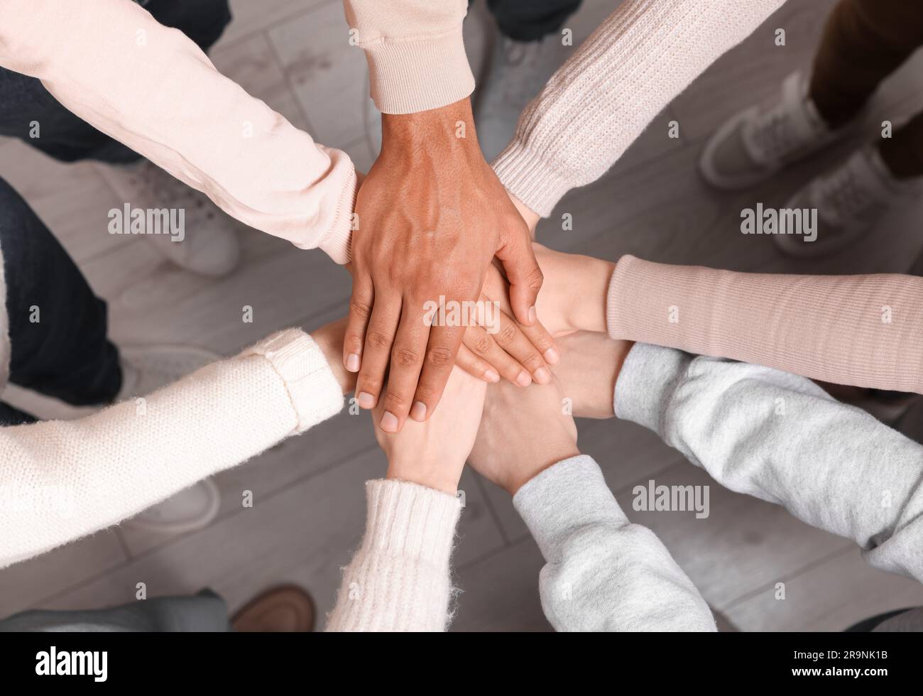 Group of multiracial people joining hands together indoors, top view ...