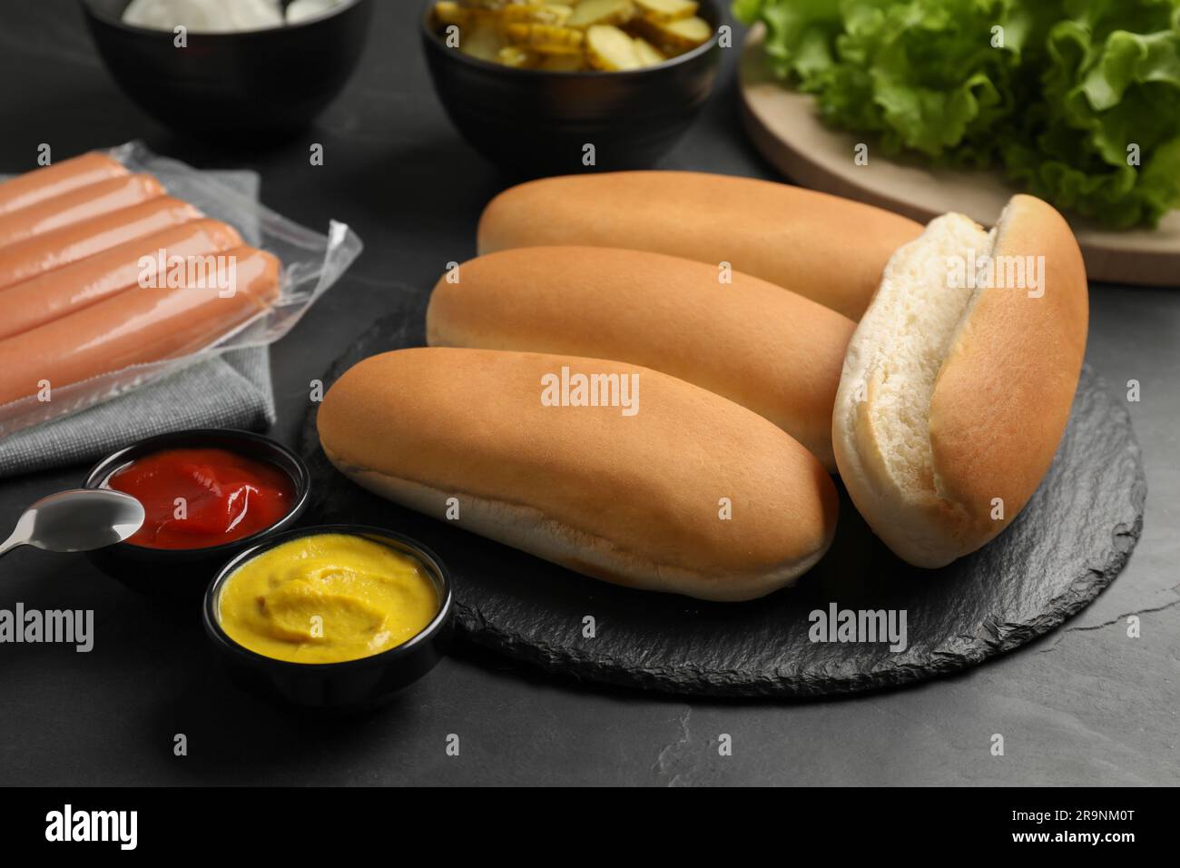 Different tasty ingredients for hot dog on dark table Stock Photo - Alamy