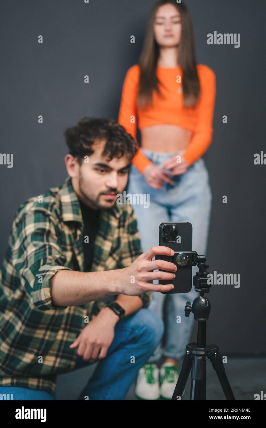 Young man and woman taking photo on professional photo camera while ...