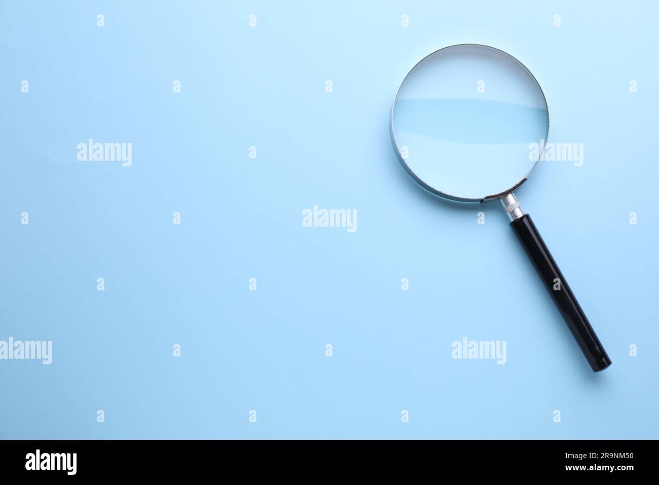 Magnifying glass on light blue background, top view. Space for text ...