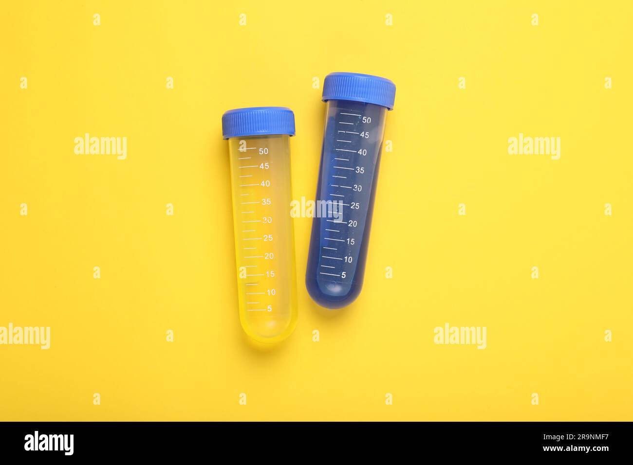 Test tubes with colorful liquids on yellow background, flat lay. Kids ...