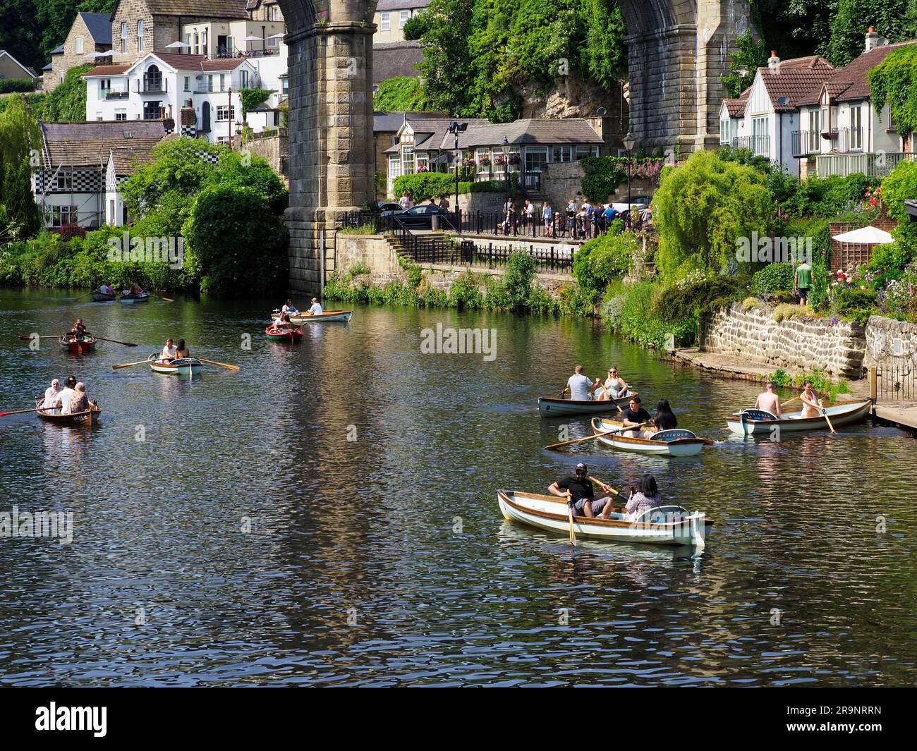 People rowing on the River Nidd below the railway viaduct on a sunny ...