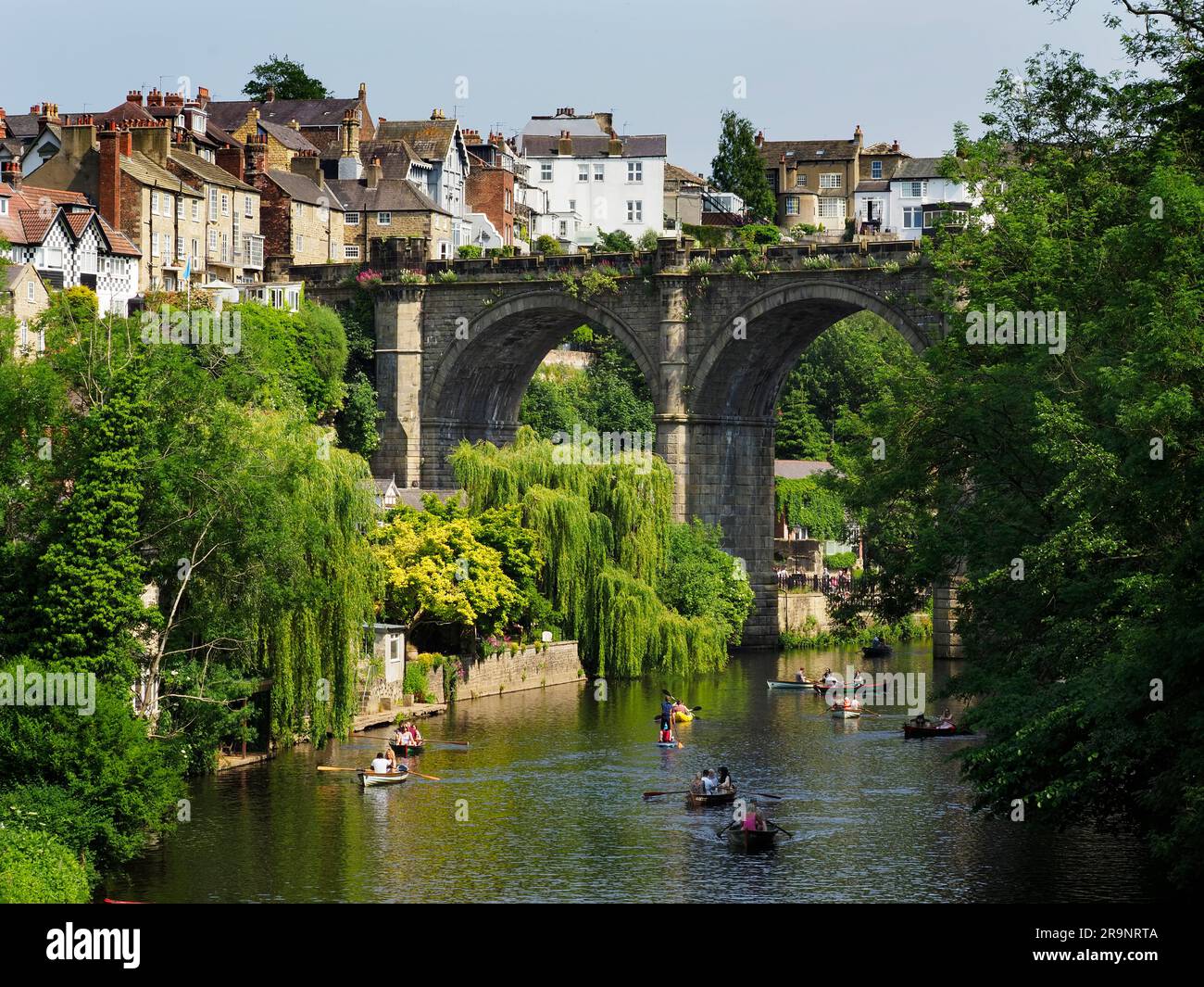 People rowing on the River Nidd below the railway viaduct on a sunny ...