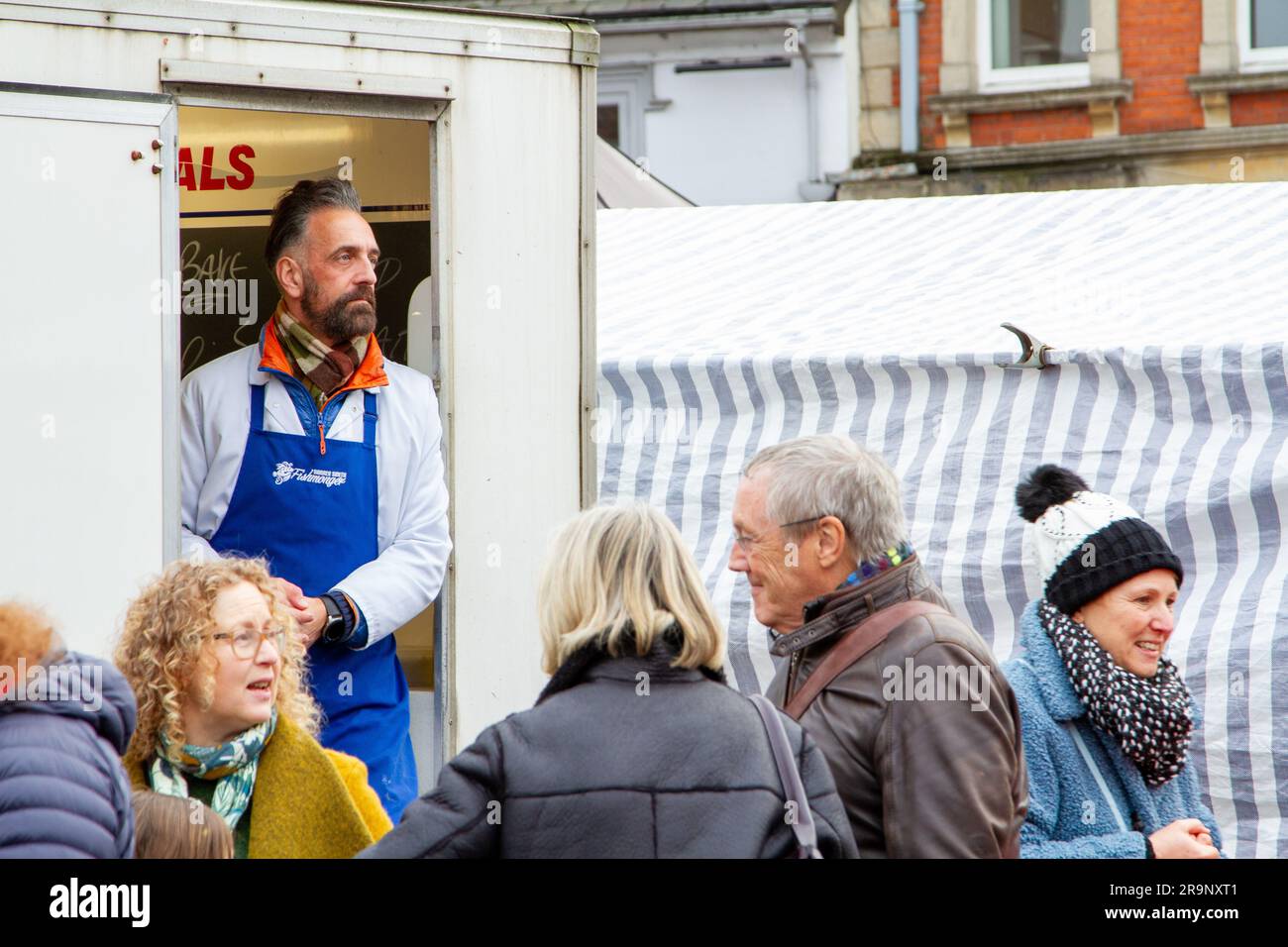 On a Suffolk street market a fishmonger stallholder looks into the ...
